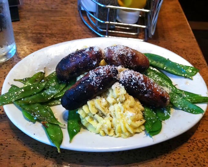 These aren't just any sausages. Plump, glistening bangers nestled against buttery mashed potatoes and vibrant snap peas—comfort food that hugs you from the inside.