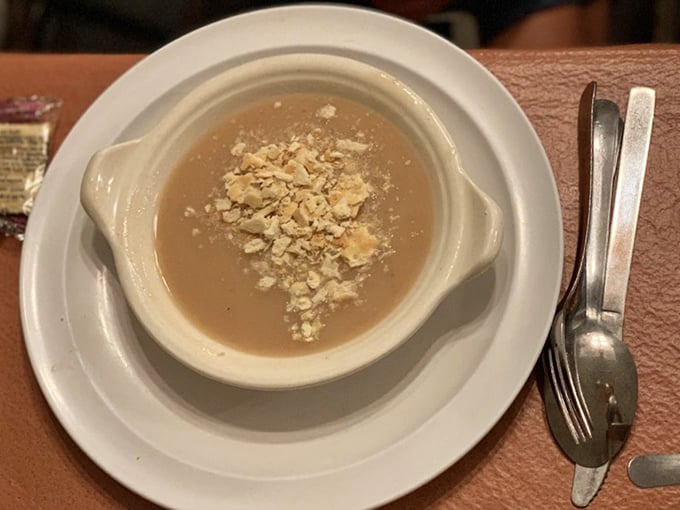 The bean soup arrives in a rustic crock, topped with crumbled crackers – humble beginnings for a meal that builds to epic proportions.