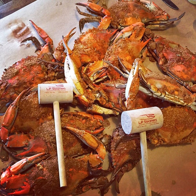 The wooden mallets stand ready for battle amid a sea of spice-crusted blue crabs—tools for the delicious treasure hunt that awaits.