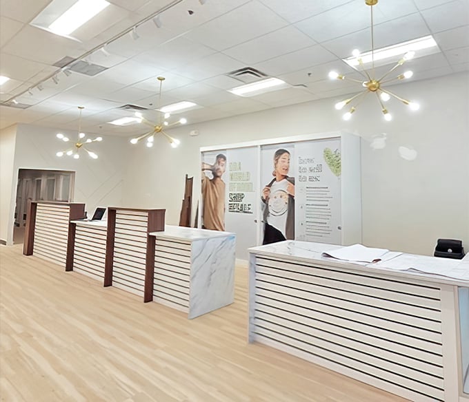 Modern elegance meets bargain hunting at Uptown Cheapskate's sleek checkout area, where stylish light fixtures and marble countertops elevate the secondhand shopping experience.