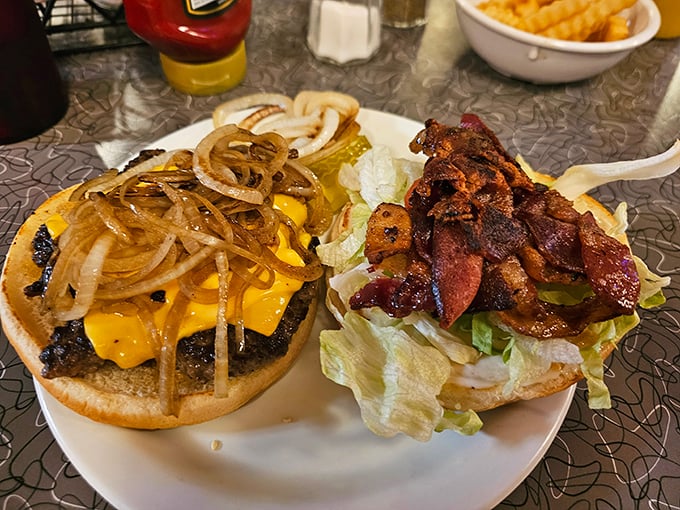 A tale of two burgers: One draped in melted cheese and grilled onions, the other loaded with bacon – both demanding to be devoured immediately.