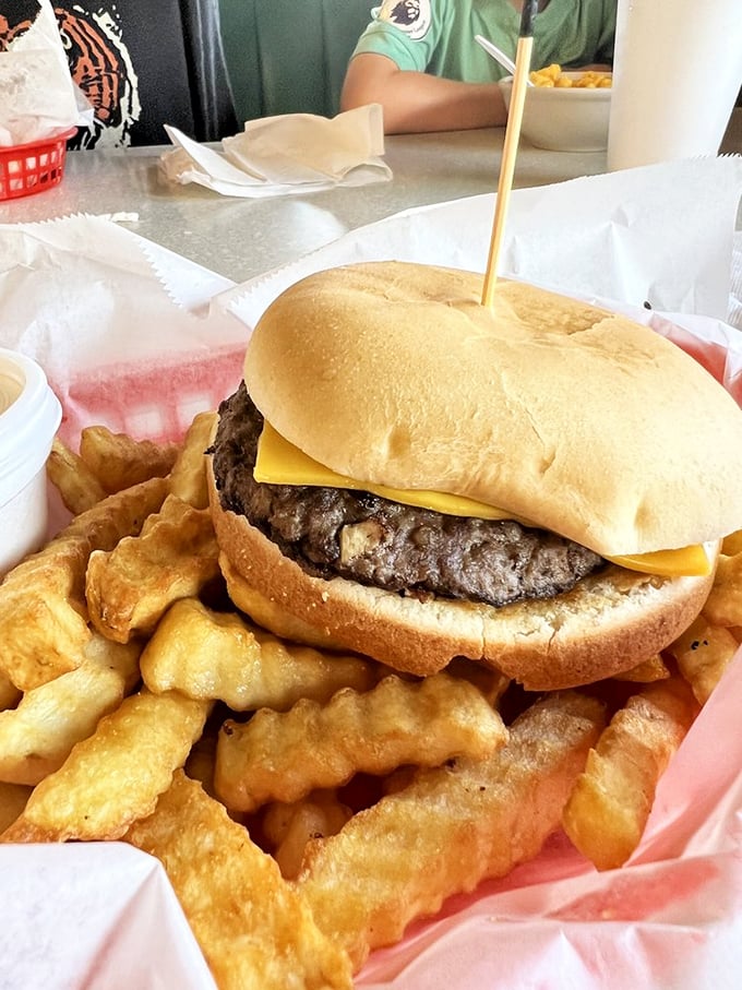 Behold the cheeseburger in its natural habitat—a thick, hand-formed patty nestled on a pillowy bun, surrounded by golden crinkle-cut sentinels.
