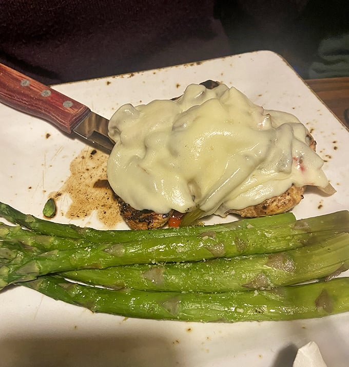 Melted cheese cascading over perfectly cooked chicken alongside vibrant asparagus spears – a plate that makes you want to slow down and savor every bite.