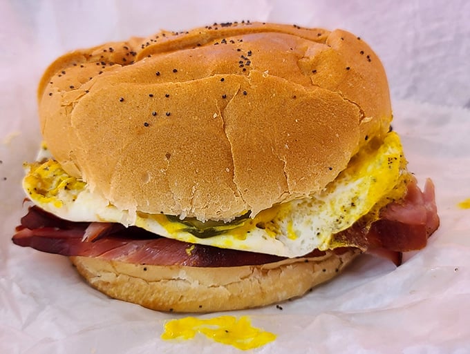 Breakfast sandwich nirvana achieved: golden egg and rosy ham nestled in a poppy seed bun. The yellow yolk threatening to create the world's most delicious mess.
