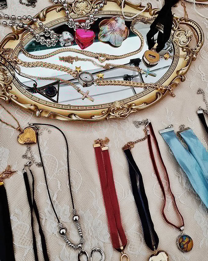 Vintage jewelry displayed on an ornate mirror—because even treasures deserve to admire themselves while waiting for new owners.
