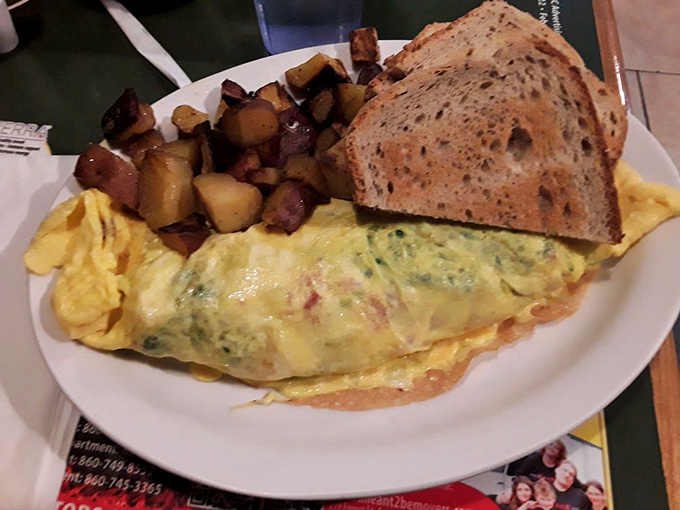 This isn't just any omelet—it's a fluffy yellow canvas painted with vibrant vegetables and melted cheese, served with home fries that could convert a carb-avoider.