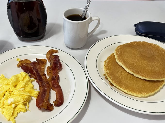 The breakfast trinity—golden pancakes, perfectly scrambled eggs, and bacon that's achieved that mythical balance between crisp and chewy.