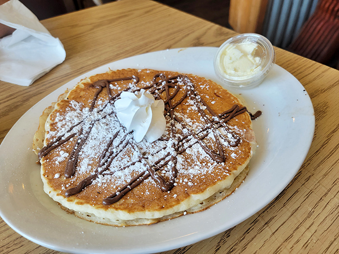 These pancakes aren't just breakfast, they're edible therapy—fluffy discs of joy topped with chocolate drizzle and a dusting of powdered sugar.