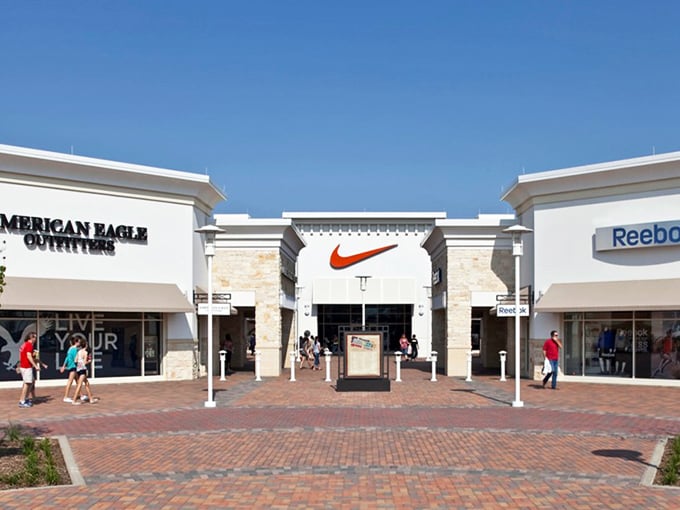 Nike's swoosh promises athletic dreams at outlet prices, where performance meets affordability under Texas skies.