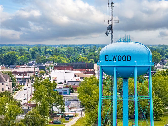 Hydration station celebration! Elwood's baby-blue water tower stands like a mid-century modern sculpture against nature's green canvas, proudly announcing "you've arrived" to passing clouds.