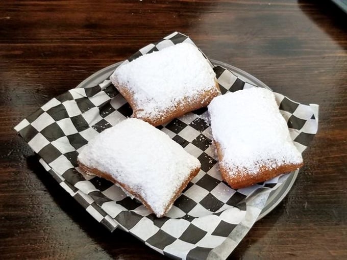 Pillowy beignets under a snowfall of powdered sugar—three perfect squares of fried dough that make you understand why New Orleans never sleeps.
