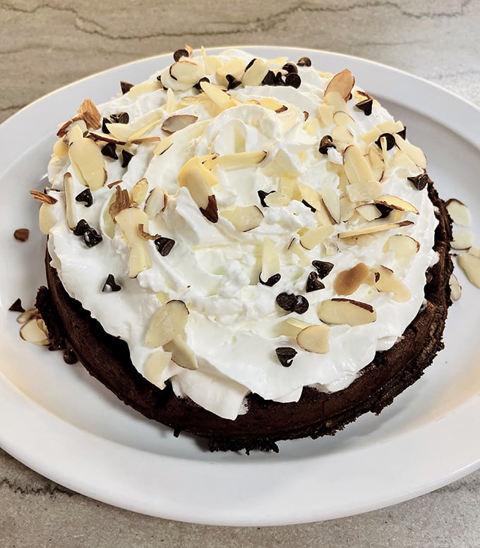 This chocolate-topped Belgian waffle with whipped cream and almonds isn't breakfast—it's dessert with an alibi. Morning indulgence at its finest.