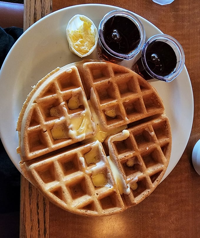 Belgian waffles that achieve the impossible balance—crisp exterior, fluffy interior—paired with butter melting into those perfect squares like sunshine into your day.
