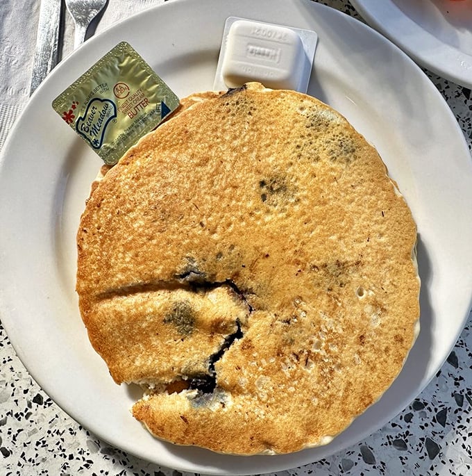 This pancake isn't just big—it's the size of a small frisbee, with blueberries that burst like tiny flavor bombs.