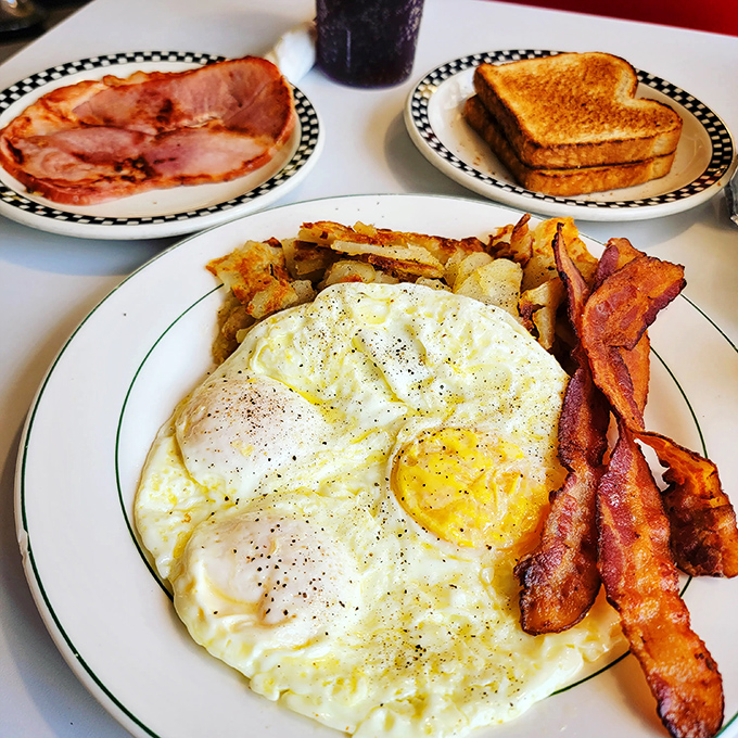 The breakfast trinity – perfectly fried eggs with that sunshine yellow center, crispy bacon, and home fries that somehow manage to be both crispy and tender.