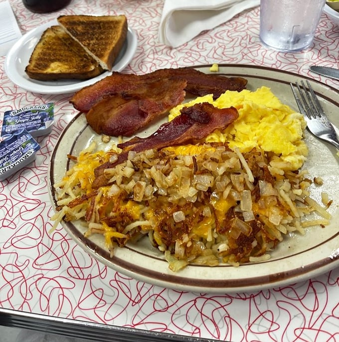 The breakfast trinity—crispy hashbrowns, fluffy eggs, and bacon cooked to perfection—proof that some relationships are meant to last forever.