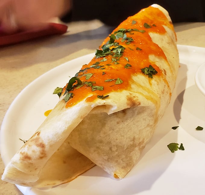 This breakfast burrito, dressed in vibrant orange sauce and fresh herbs, is what happens when morning hunger meets culinary creativity.