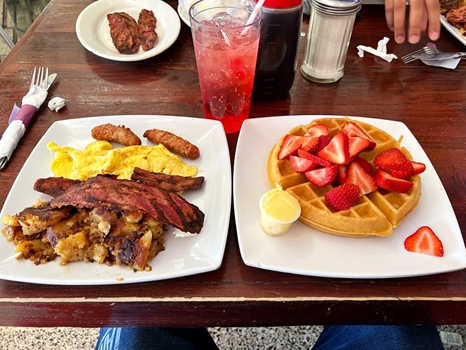 Breakfast perfection on a plate: golden waffles with strawberries alongside eggs and bacon—the breakfast equivalent of having both Netflix AND HBO Max.