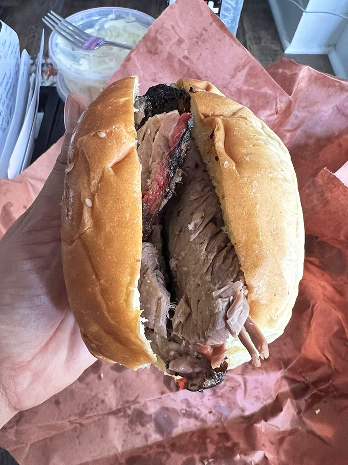 This sandwich isn't messing around – the brisket is practically spilling out like it's trying to make a break for it before you can devour it.