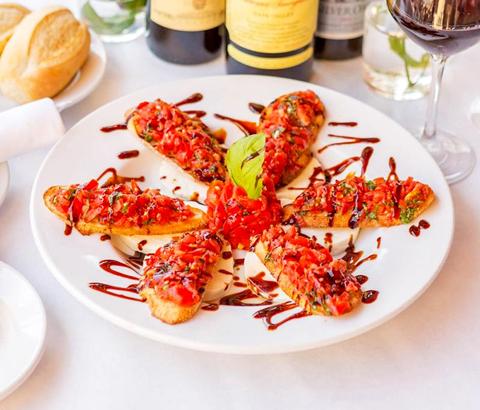 Bruschetta arranged like a sunburst – each piece a crunchy canvas for the summer-sweet tomatoes and balsamic drizzle that makes you want to lick the plate.