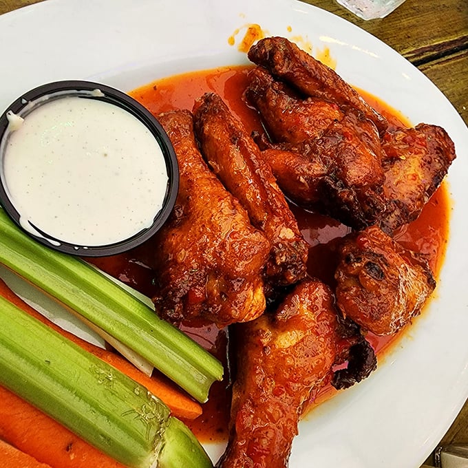 Buffalo wings done right: glistening with sauce, accompanied by cooling celery and carrots—proof that sometimes the classics need no improvement.