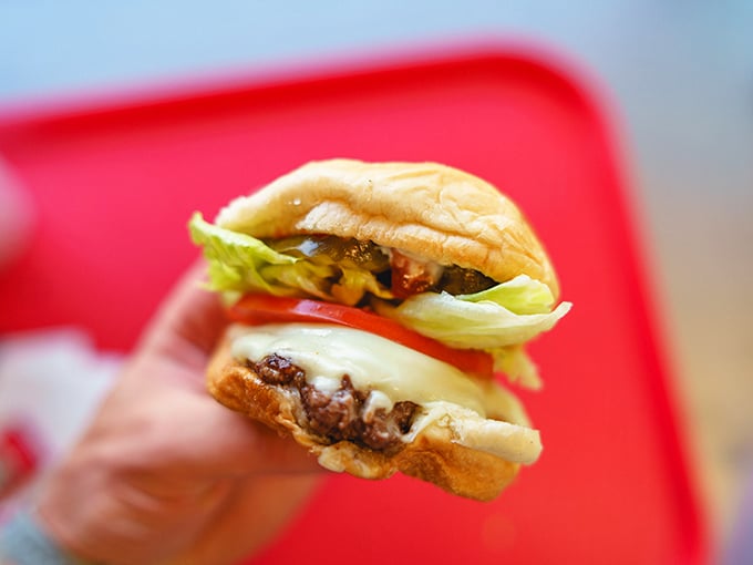 Behold the humble cheeseburger in its natural habitat—melty cheese, fresh veggies, and a perfectly grilled patty that puts fast food chains to shame.