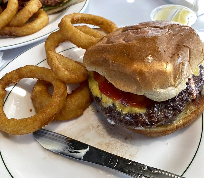 This isn't just a burger—it's architecture. The perfect stack of beef, cheese, and fresh toppings with onion rings that could double as delicious bracelets.