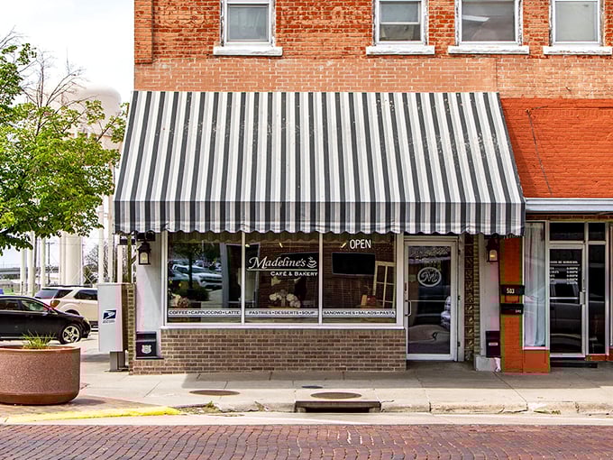 Madeline's striped awning isn't just shade—it's an invitation to slow down. Coffee tastes better when sipped beneath classic small-town architecture.