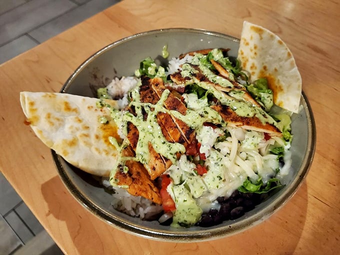 A fiesta in a bowl: seasoned rice topped with grilled chicken, fresh vegetables, and a drizzle of creamy sauce that ties everything together beautifully.