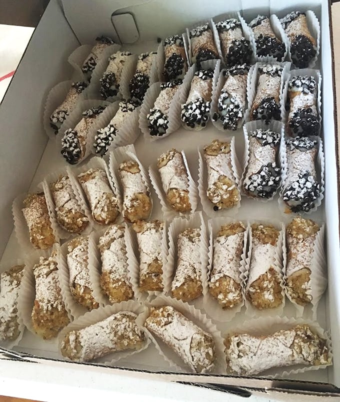 Cannoli lined up like delicious soldiers, ready to march straight into your heart with their chocolate-dipped ends and powdered sugar armor.