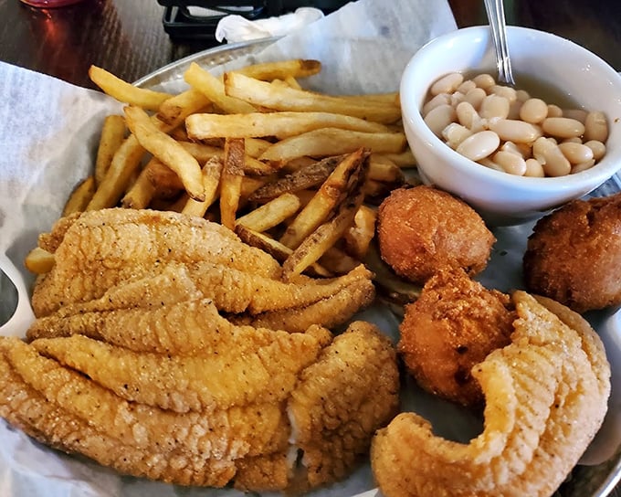 A plate that celebrates the marriage of land and sea—catfish strips, white beans, and hush puppies creating the comfort food trifecta of champions.