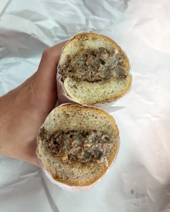 When cut in half, the cheesesteak reveals its soul—perfectly melted cheese binding seasoned beef in a sacred sandwich covenant.