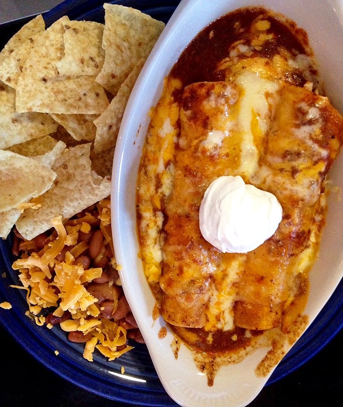 These enchiladas aren't just covered in cheese—they're wearing a melty security blanket that makes Monday blues disappear faster than dessert at a family reunion.