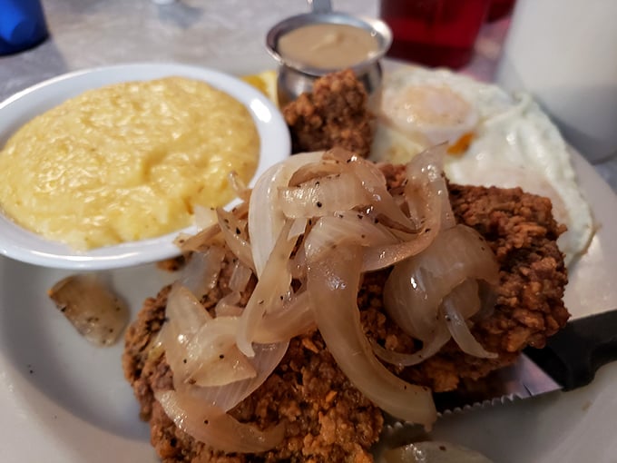 Country fried steak with caramelized onions and gravy alongside scrambled eggs and grits—the breakfast equivalent of a warm Southern hug.
