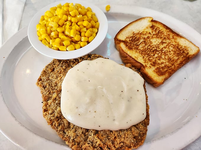 Country fried steak smothered in gravy with a side of sweet corn and Texas toast – a plate that says "you'll need a nap after this" in the most delicious way possible.