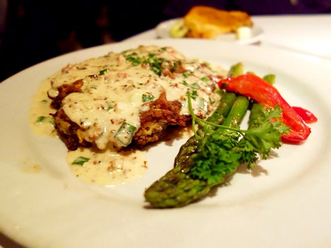 Comfort food elevated to art form—crispy exterior giving way to tender meat beneath a blanket of creamy sauce. Vegetables provide the illusion of virtue.