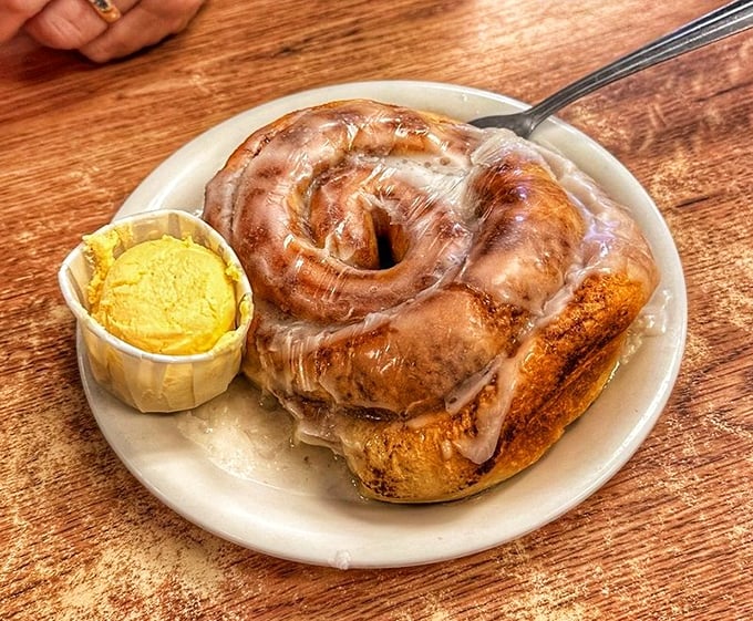 A cinnamon roll that's basically dessert masquerading as breakfast. The glaze glistens like morning dew on a pastry that's bigger than most people's daily caloric needs.