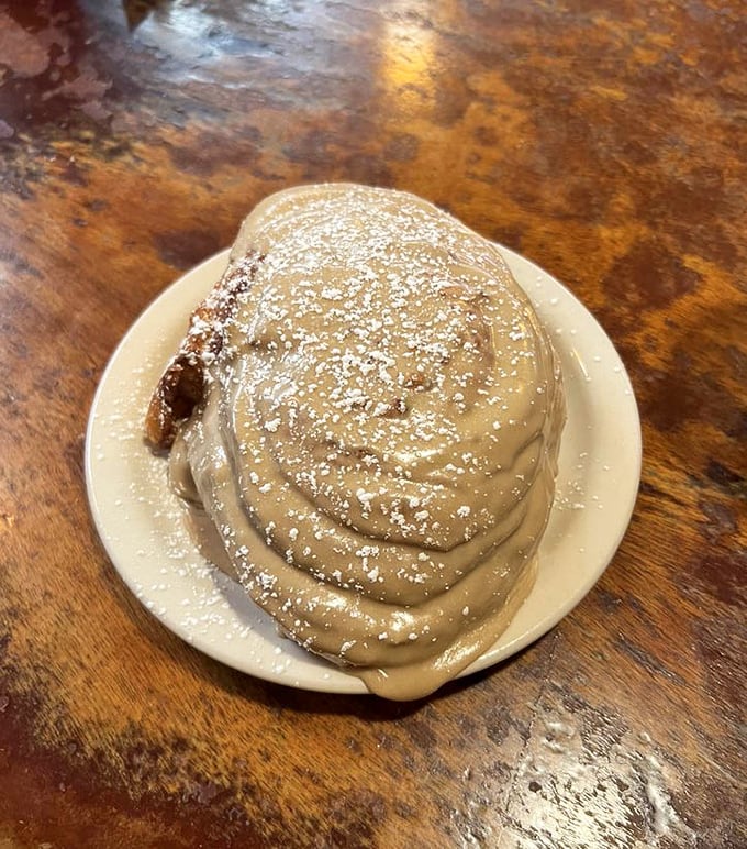This cinnamon roll isn't just breakfast – it's dessert with a permission slip, a spiral of morning joy dusted with powdered sugar.