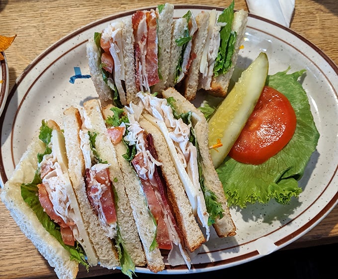 The club sandwich: three stories of deliciousness that makes skyscrapers jealous, with a pickle standing guard like it knows what it's protecting.
