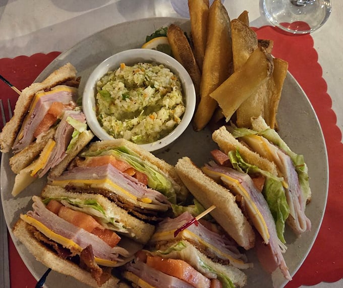 The club sandwich arrives like an architectural marvel—layers of fresh ingredients flanked by crispy fries and homemade coleslaw that doesn't know it's a side dish.