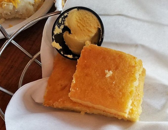 Cornbread so buttery and golden it could finance your retirement. The scoop of butter melting on top is just showing off.