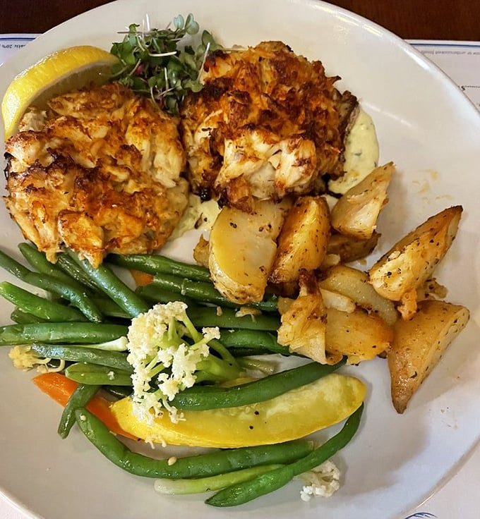 Crab cakes that are actually crab, imagine that! Golden-brown perfection alongside roasted potatoes and fresh vegetables – the holy trinity of seafood satisfaction.