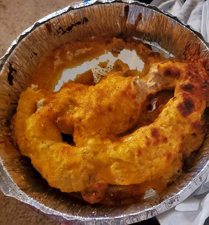 This crab-topped creation, nestled in its foil boat, proves that sometimes the best culinary innovations happen when seafood meets comfort food.