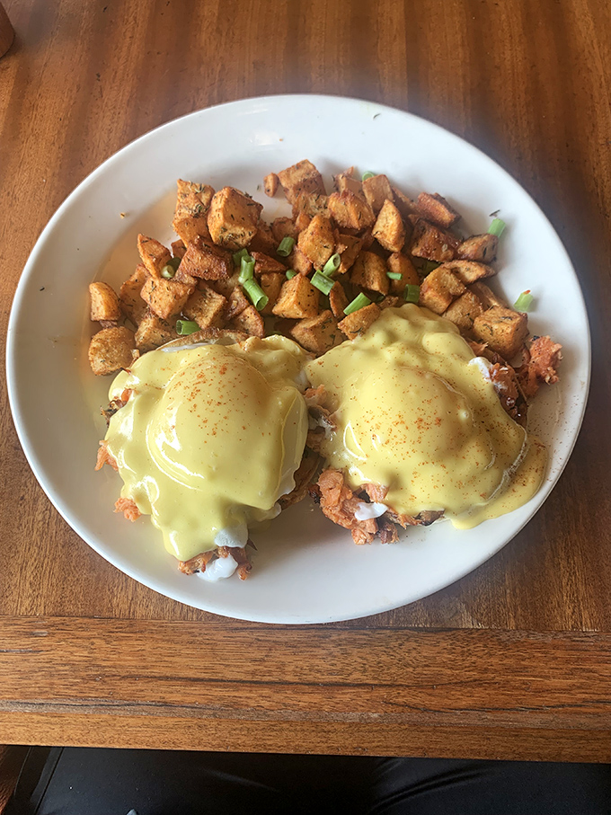 Eggs Benedict done right – perfectly poached eggs nestled on a base, draped in hollandaise that cascades like a yellow waterfall of deliciousness.