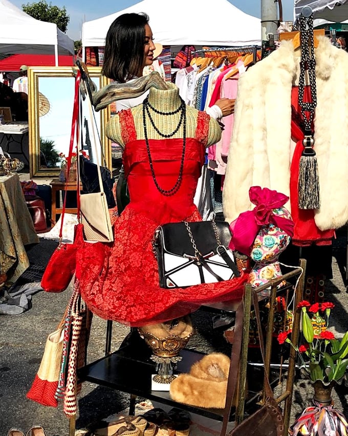 A crimson dress stands sentinel among vintage accessories, like a Hollywood starlet waiting for her comeback role.