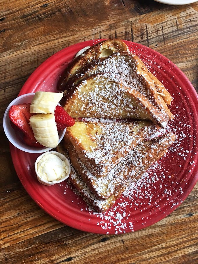 French toast that's dressed for success—powdered sugar snow, fresh fruit accessories, and that golden-brown exterior that whispers, "Yes, this is worth the calories."