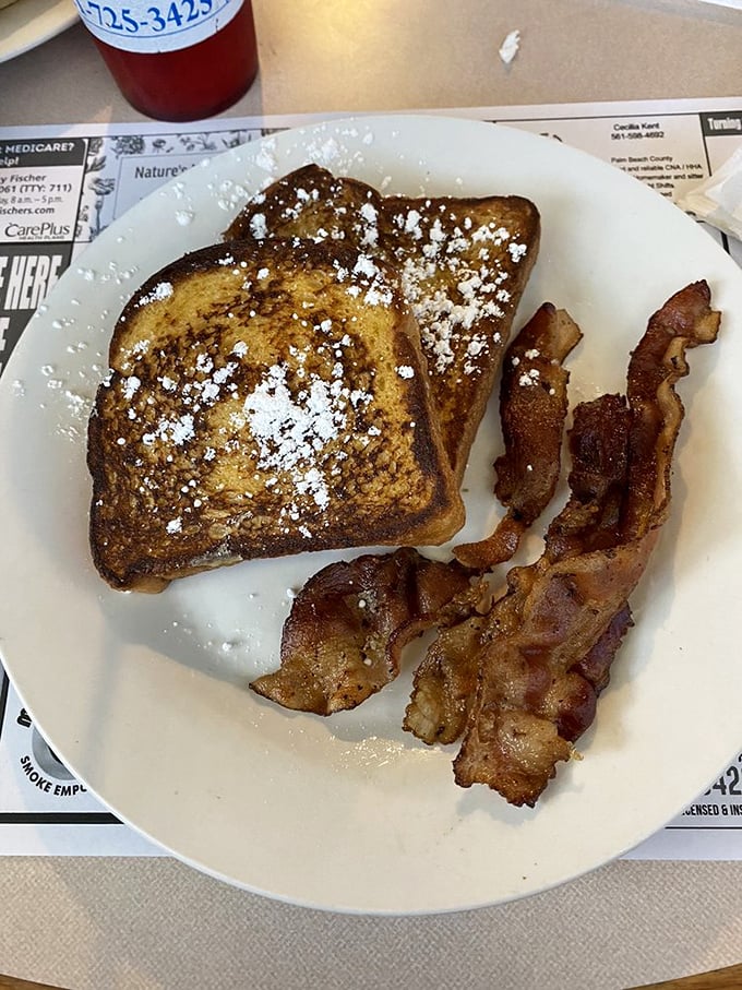 French toast dusted with powdered sugar alongside crispy bacon – proof that the sweet-savory combination is humanity's greatest culinary achievement.