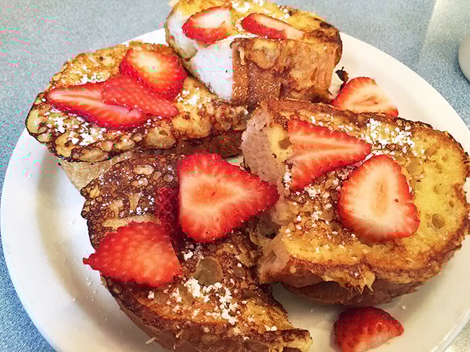 French toast that makes you question all other breakfast choices—golden, crisp edges giving way to custardy centers, crowned with fresh strawberries.