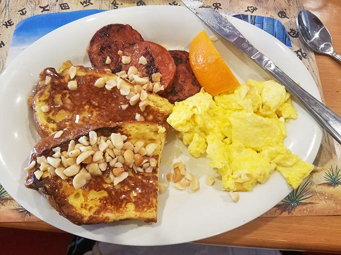 French toast dusted with powdered sugar and topped with macadamia nuts, paired with Portuguese sausage—a sweet and savory island romance on a plate.