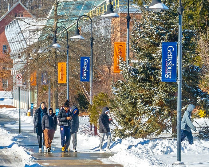 Gettysburg College banners flutter in the winter air as students navigate snowy pathways, continuing a tradition of learning that predates the famous battle.